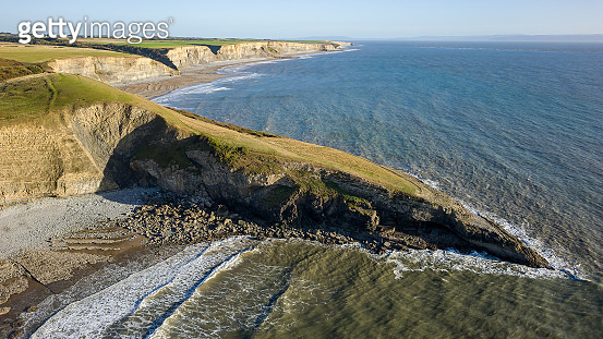 Aerial view of limestone cliffs and a rock covered sandy beach 이미지 ...