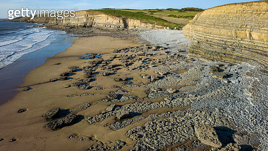 Aerial view of large limestone cliffs and a sandy beach next to the sea ...