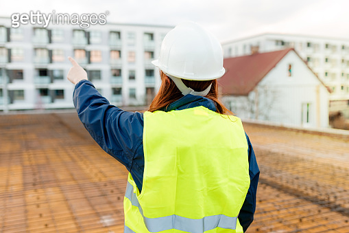 Architect redhead woman wearing contractor white helmet and safety ...