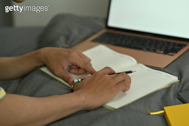 Cropped image of a university student doing homework with a white blank ...