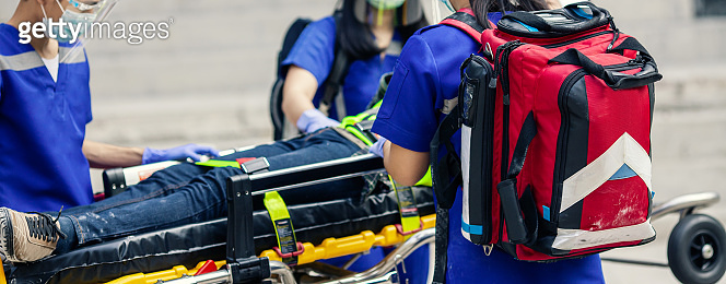 Paramedic team moving worker is patient lying on ambulance stretcher ...