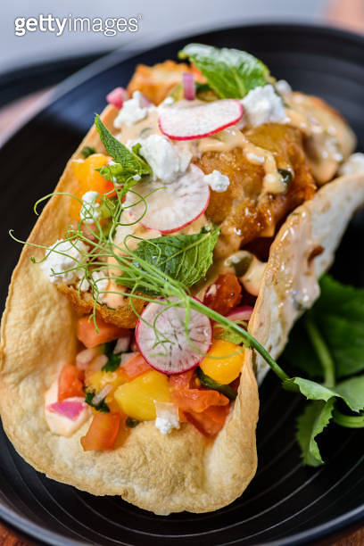 Fish taco with salsa salad, feta cheese, sriracha sauce in a crispy ...