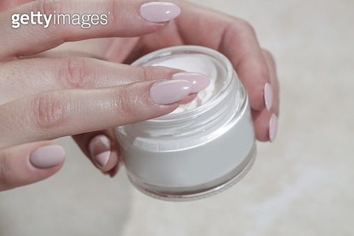 Close up of woman's hand is taking cream from a jar with her finger ...