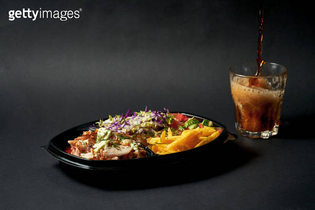 Shawarma meat in a delivery box with fries, lettuce and hummus on a ...