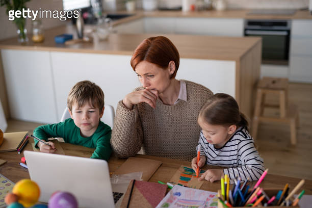 Mother of little children supervising them when distance learning and ...