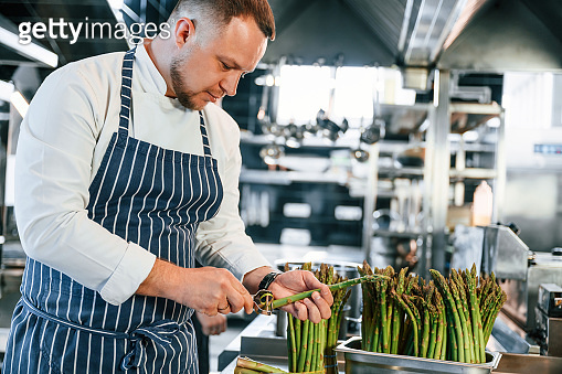 Slicing and cutting asparagus. Chef is on the kitchen preparing food ...