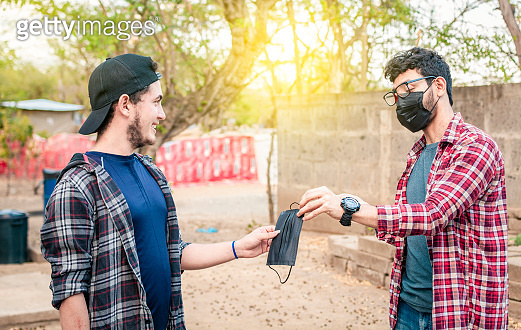 Two young people giving each other a mask, image of a young man giving ...