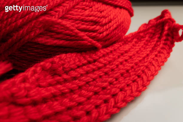Close-up of an unknitted piece of wool next to a ball of yarn. Red wool ...
