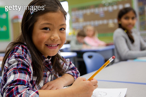 Portrait smiling, happy elementary girl student doing homework at desk ...