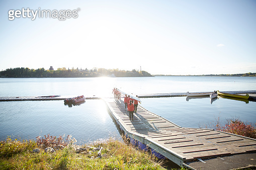 Female rowing team carrying scull on dock at sunny river waterfront 이미지 ...
