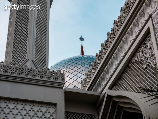 the dome of the mosque behind the white building with batik ornaments ...