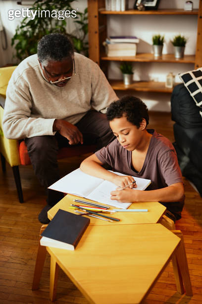 Smart African boy doing his math homework with a little help of his ...