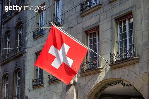 Red Swiss flag hanging from building facade 이미지 (1411158935) - 게티이미지뱅크