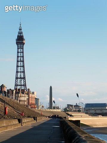 view of blackpool tower from the promenade with town buildings in ...