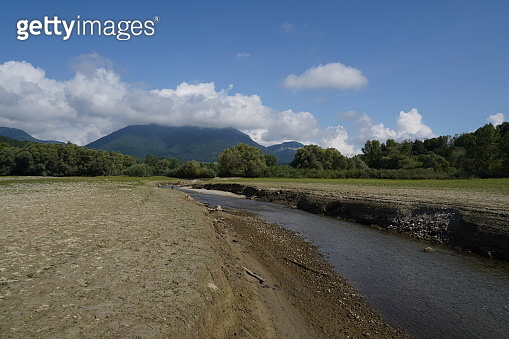 Arid or dried up muddy bottom of small river channel to supply water to ...