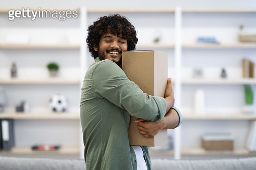 Ecstatic young indian man hugging box at home 이미지 (1372362760) - 게티이미지뱅크