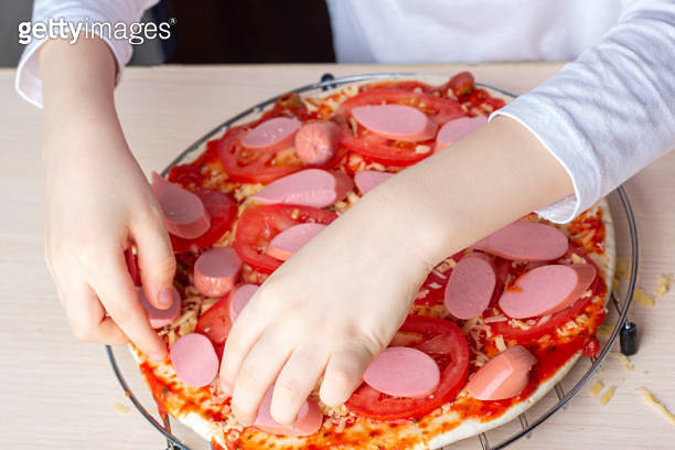Kid's hands sprinkle cheese (ingredients) on pizza dough. Process of ...