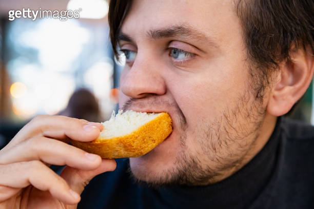 Male man eats fresh white bread. Homemade sourdough bread. Hungry ...