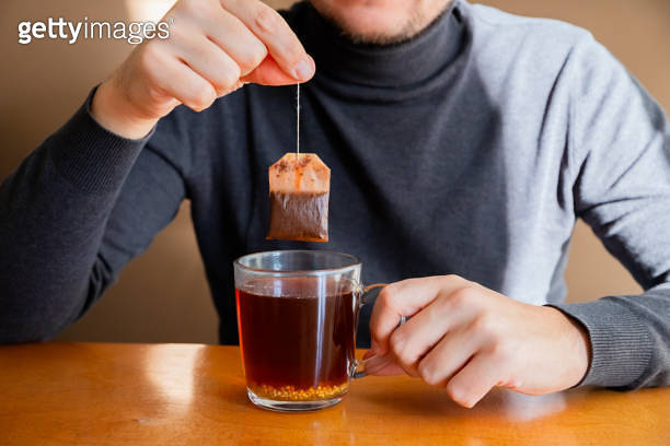 Male man holding wet teabag, brewing black vitamin tea with bag in ...