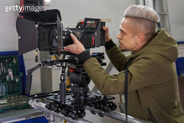 young caucasian man videographer controls shooting on the monitor ...
