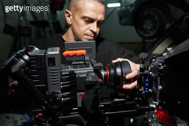 young caucasian male videographer changing lenses on a professional ...