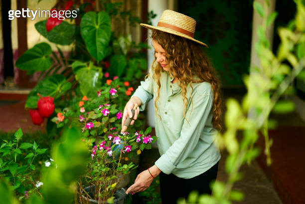 Young woman gardener in straw hat holding hand shovel taking care of ...