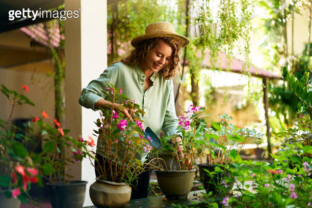 Young woman gardener in straw hat holding hand shovel taking care of ...