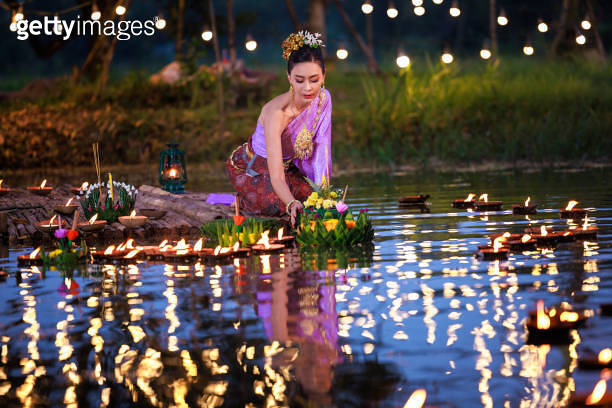 Thai woman holding a krathong sitting on a raft by the river, Asian women in traditional Thai ...