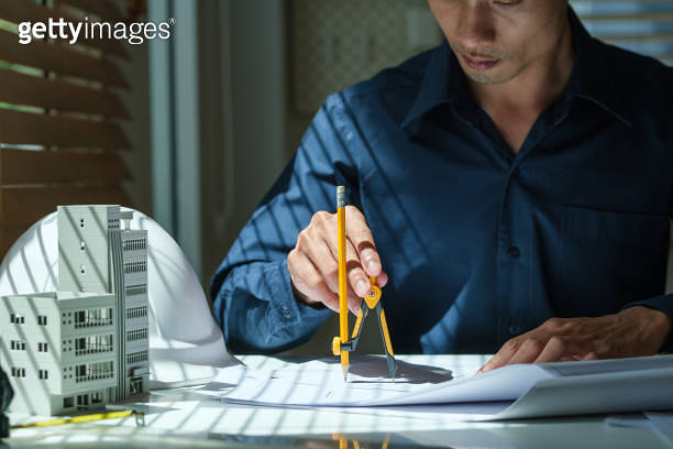 Engineer man hand using geometry compass while working with blueprints ...