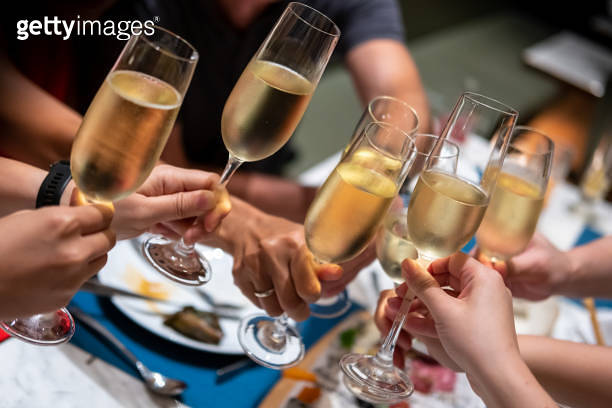 A group of people raise a toast with glasses of Prosecco or sparkling ...