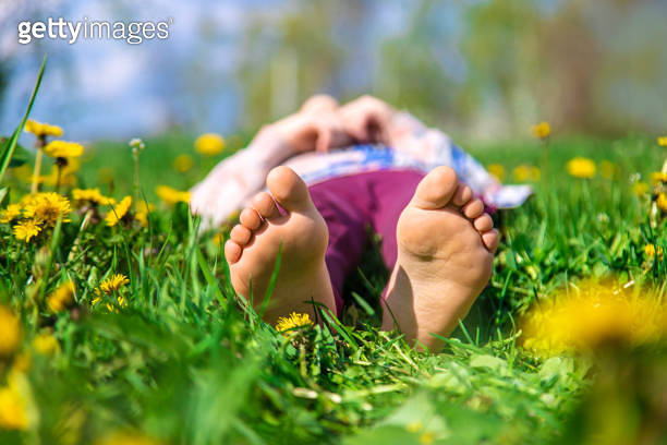 Child feet on the grass in the spring dandelions garden. Selective ...