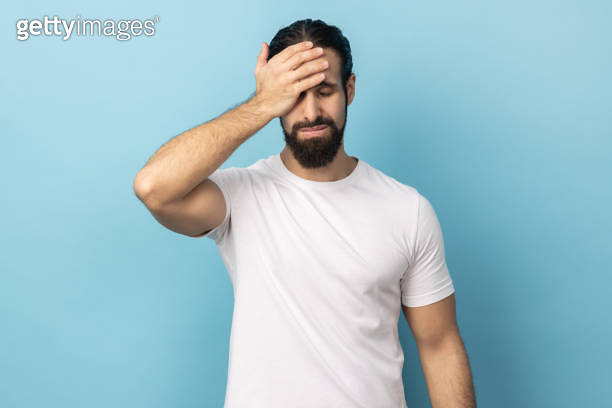 Man standing with facepalm gesture, feeling regret and sorrow, blaming ...
