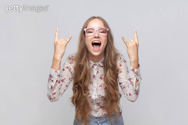 Woman standing with rock sing, screaming yelling with excited facial ...