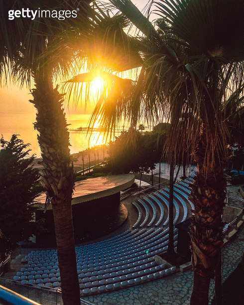 Beautiful view of amphitheater on the coast with palm silhouettes ...