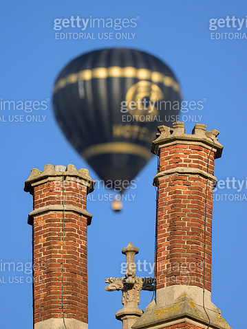 Two chimneys in front of a hot air balloon floating in the distance 이미지 ...