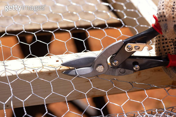 Working a worker cutting metal mesh with scissors for metal (1867781248 ...