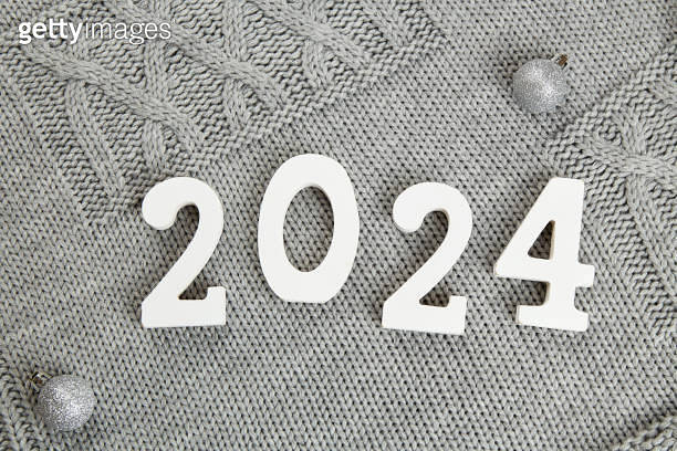 Wooden numbers 2024 and silver Christmas balls on a gray knitted ...