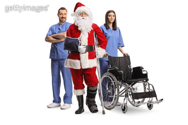 Injured santa claus with a foot brace and arm sling standing with a ...