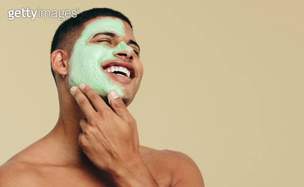 Male skincare routine: Happy young man smiling while pampering his skin ...