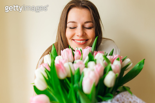 Woman with Spring Flower bouquet. Happy surprised model woman smelling ...