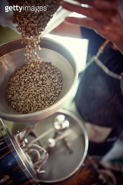 close up detail of whole grain coffee spilling from plastic dish into a ...