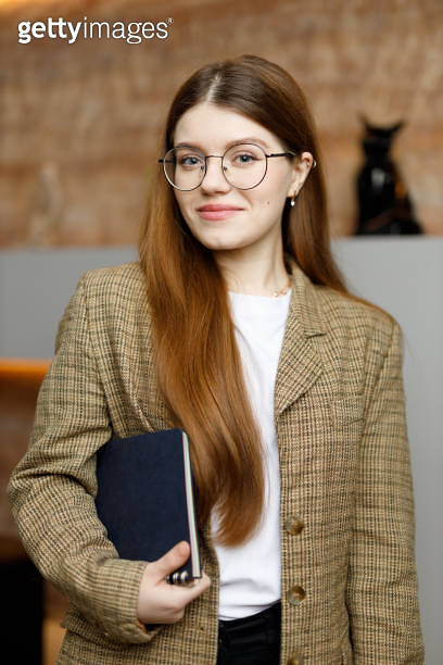 Portrait of a young woman intern with a notepad, a student at school ...