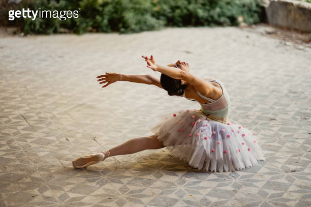 Ballerina dancing in a back bend position while wearing tutu and pointe ...