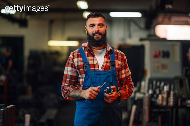 Portrait of a mechanic holding a metal ring and and a measuring tool ...