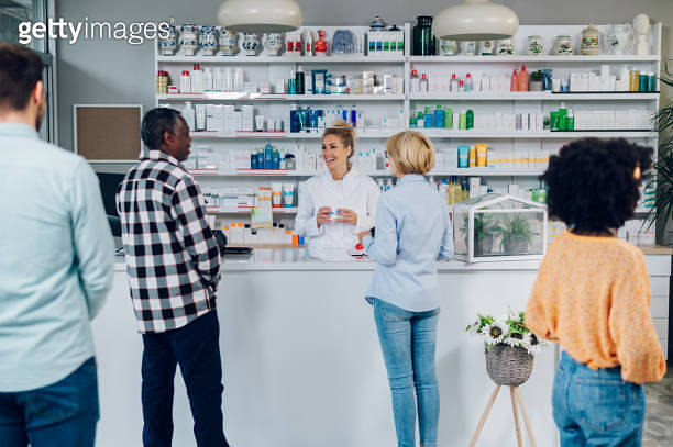 A queue of people standing in a pharmacy while shopping for medicine ...