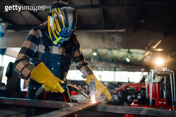 Skilled man working hard while welding a metal construction patiently ...