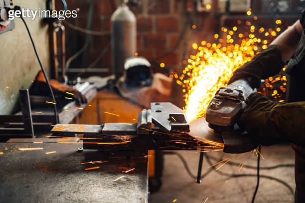 Grinding machine in action while hot sparks flying in all directions ...
