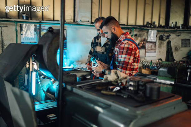 Two metal workers by a lathe machine, checking a metal cylinder. 이미지 ...