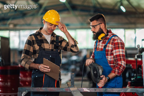 Workers checking the measurements in the notes before the production ...