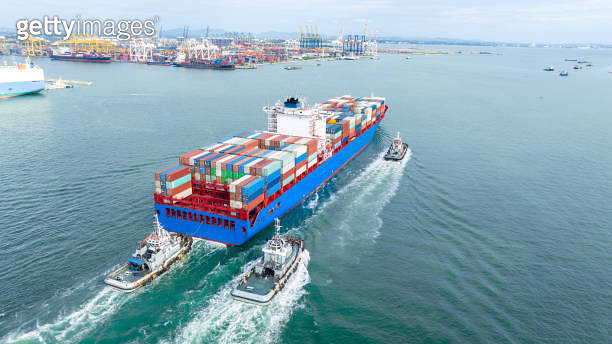Cargo container ship carrying container and running with tug boat for ...